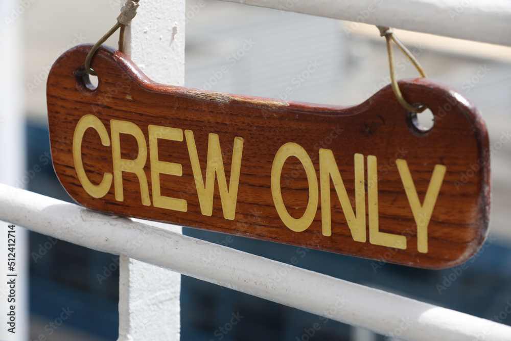 Crew only sign on a ship against a blurred background with ropes and a ...