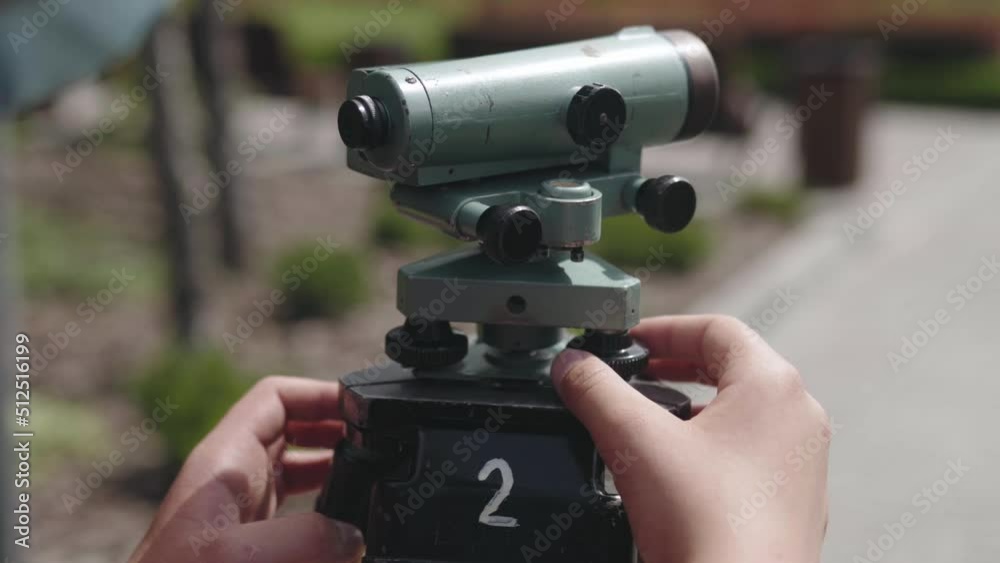 Construction worker uses vintage optical level on construction site ...