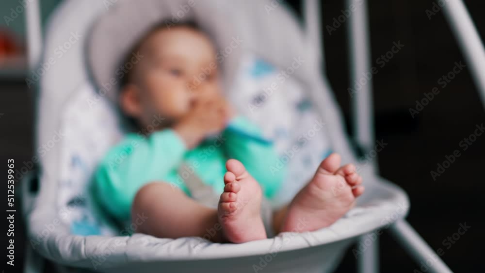 Vídeo do Stock: Adorable baby sitting in a sway chair chewing spoon ...