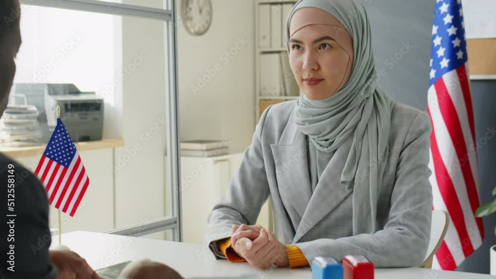 Young muslim woman in hijab walking in U.S. embassy, giving documents ...