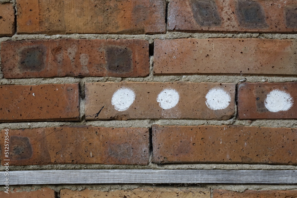 Four white graffiti dots on red brick stone wall, horizontally aligned ...