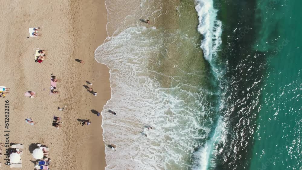 aerial footage from a drone on a sandy beach with people sunbathing and ...