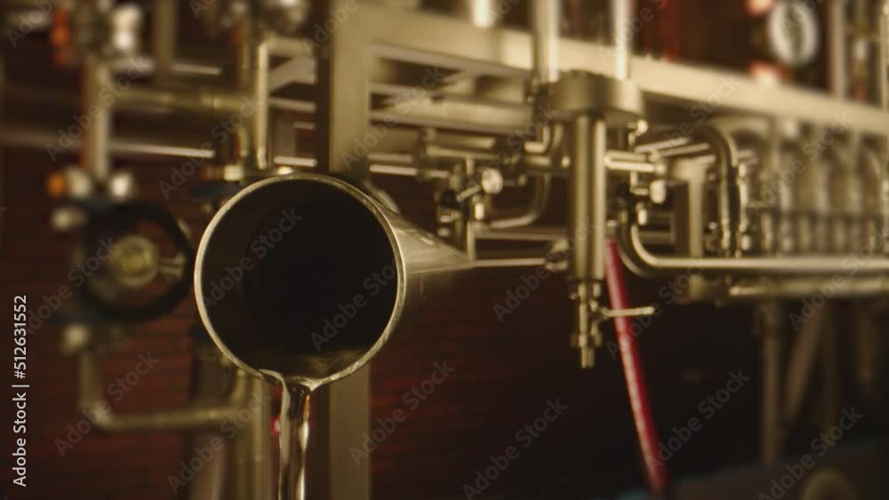 Vodka pouring from big tubes inside professional alcohol production ...