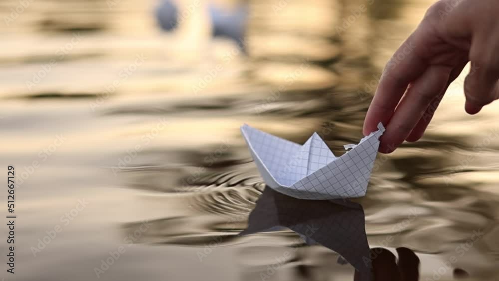 child puts a paper boat into the water. happy family fantasy kid dream ...