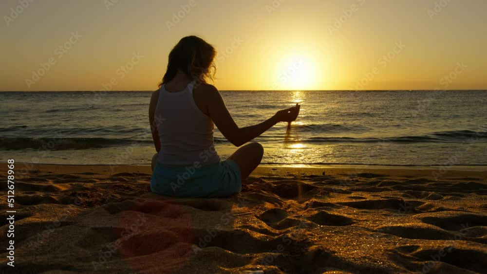 Alone woman sitting on cinematic beach at golden scenic sunset shining ...