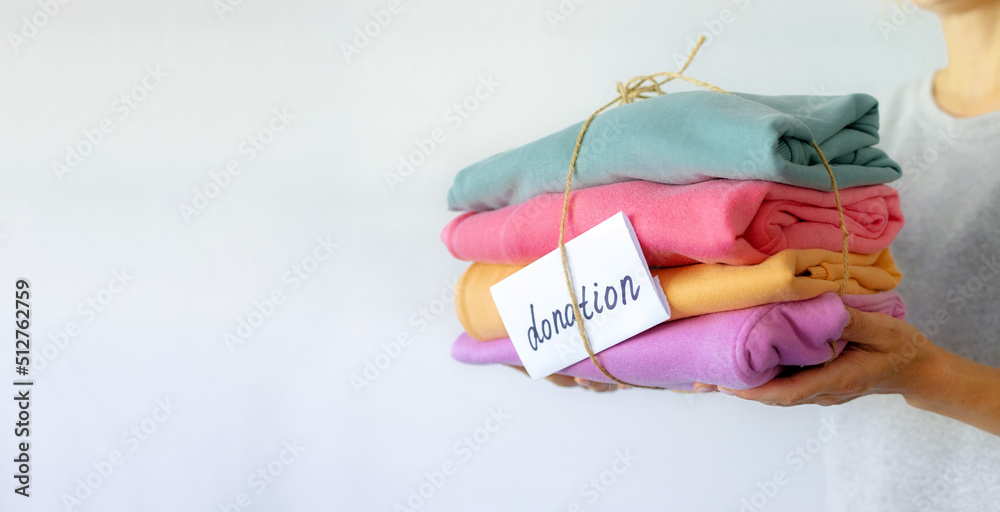 Woman's hand holding a stack of clothes. Clothes Donation, Renewable ...