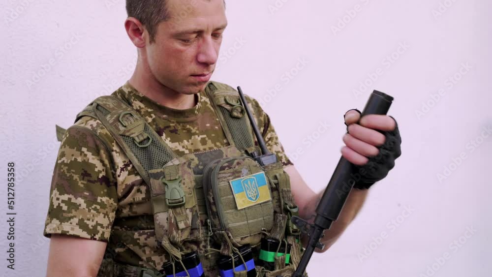 Ukrainian military man in combat camouflage and body armor attaches a ...