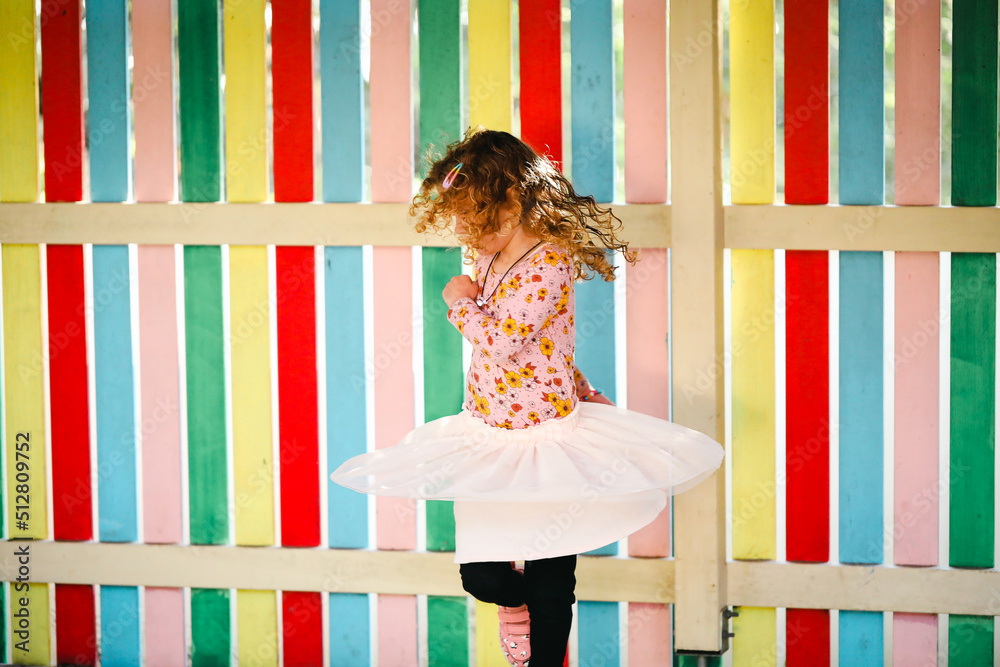 Little girl twirling in front of vibrant rainbow colored wall Stock ...