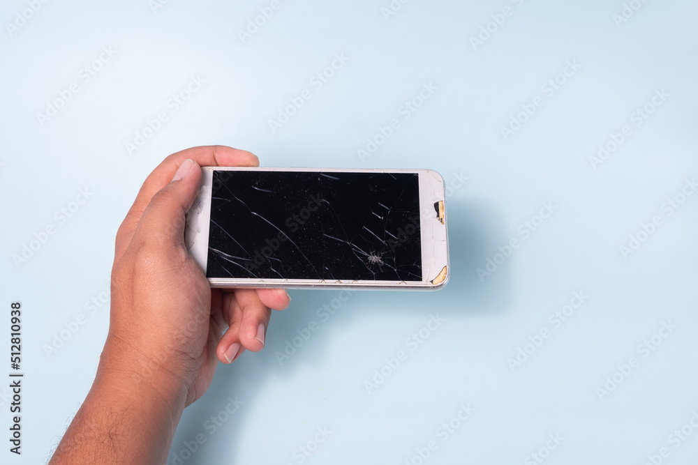 a man's hand is using a mobile phone that has a broken screen. The ...