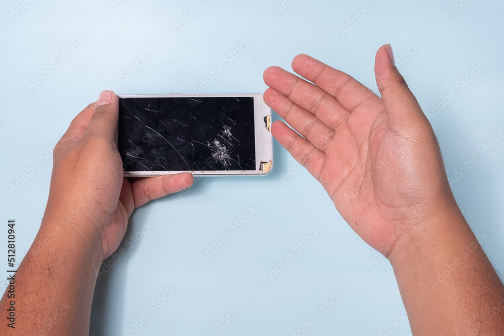 a man's hand is using a mobile phone that has a broken screen. The ...