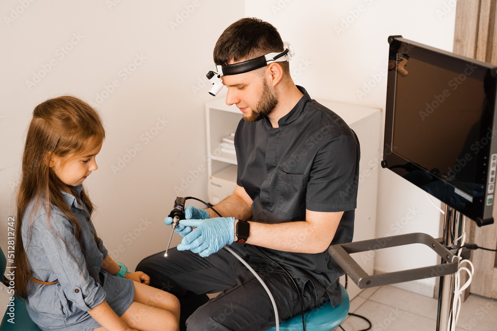ENT doctor otolaryngologist with headlight showing to child endoscope ...