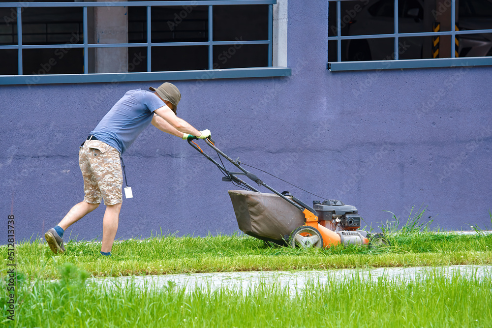Man mowing grass with lawn mower. Worker cutting grass with lawn mower ...