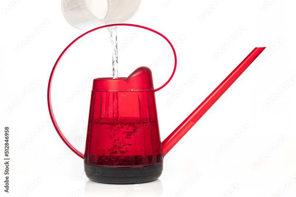 Red plastic watering can isolated on white background, being filled ...