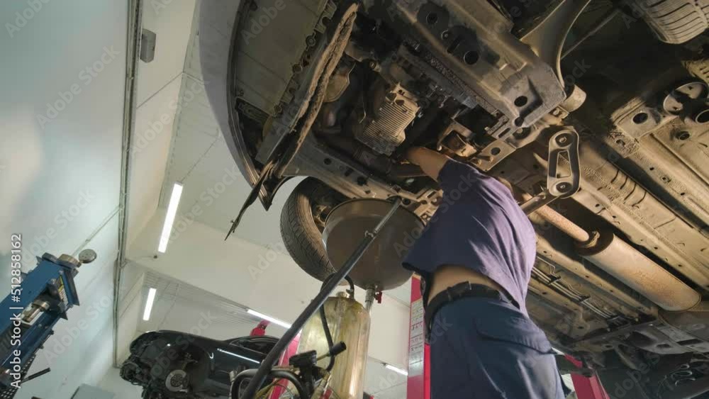 Auto mechanic is changing motor oil into a engine at car station ...