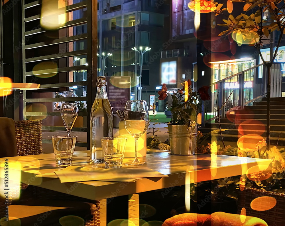 night street cafe glasseson table and flowers evning city blurred light ...