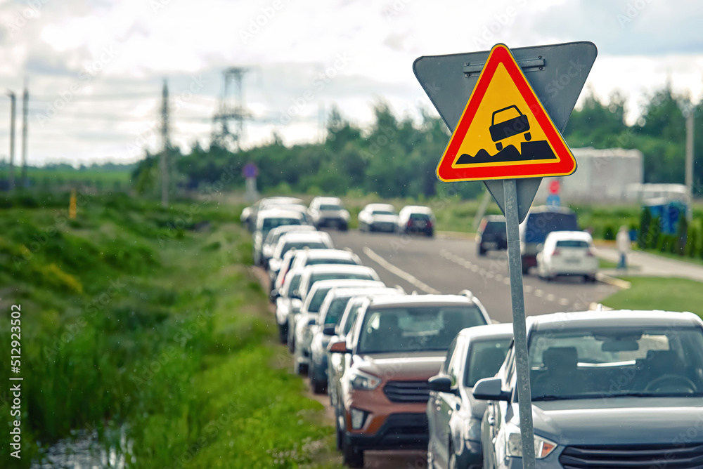 Warning sign - soft verges, traffic sign and cars parked in row along ...