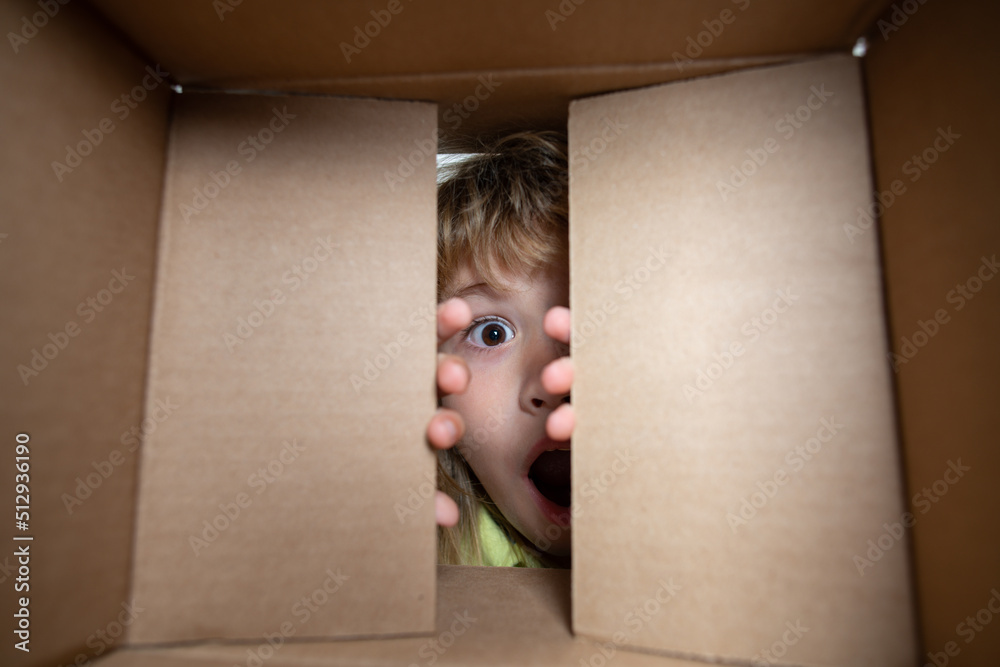 Child boy opening a carton box and looking inside, unpacking concept ...