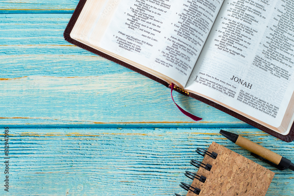 Jonah open Holy Bible Book on a rustic wooden table background with a ...
