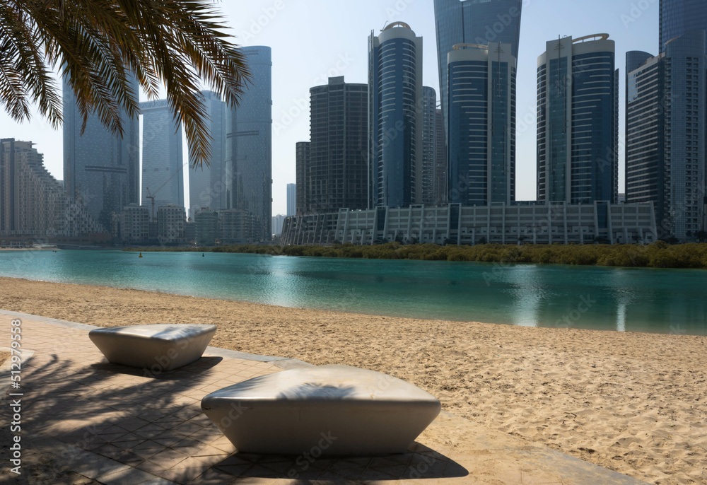 Al Reem Central park, beach walk with stone benches and a palm tree ...
