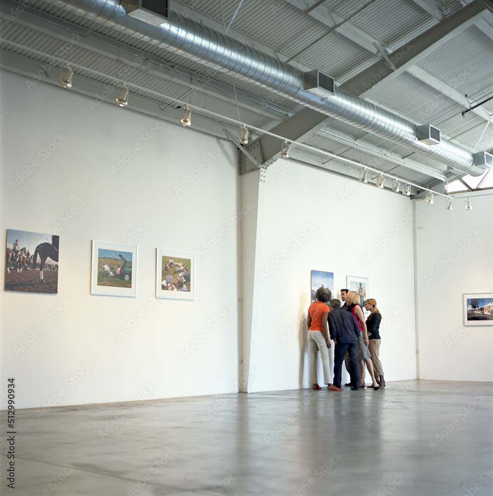 Group of people looking closely at photograph in art gallery Stock ...
