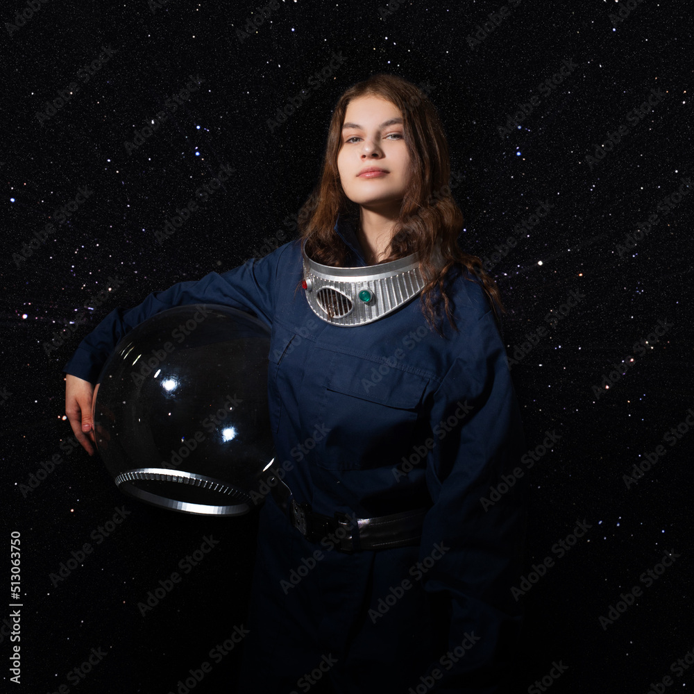 A young woman in a spacesuit and with a helmet in her hands, stands in ...