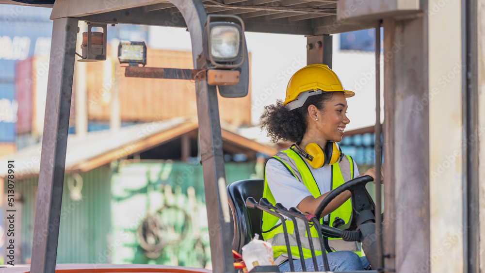 Young African American lady operates a forklift tractor to move ...
