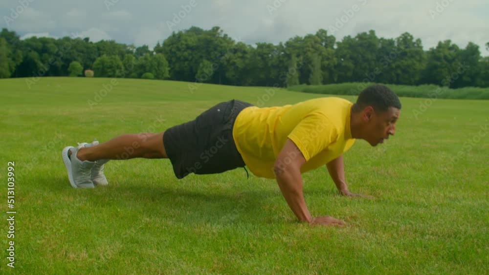 Motivated active sporty fit African man practicing advanced push up ...