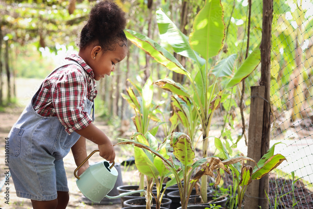 Happy African girl with black curly hair watering plant, gardener kid ...