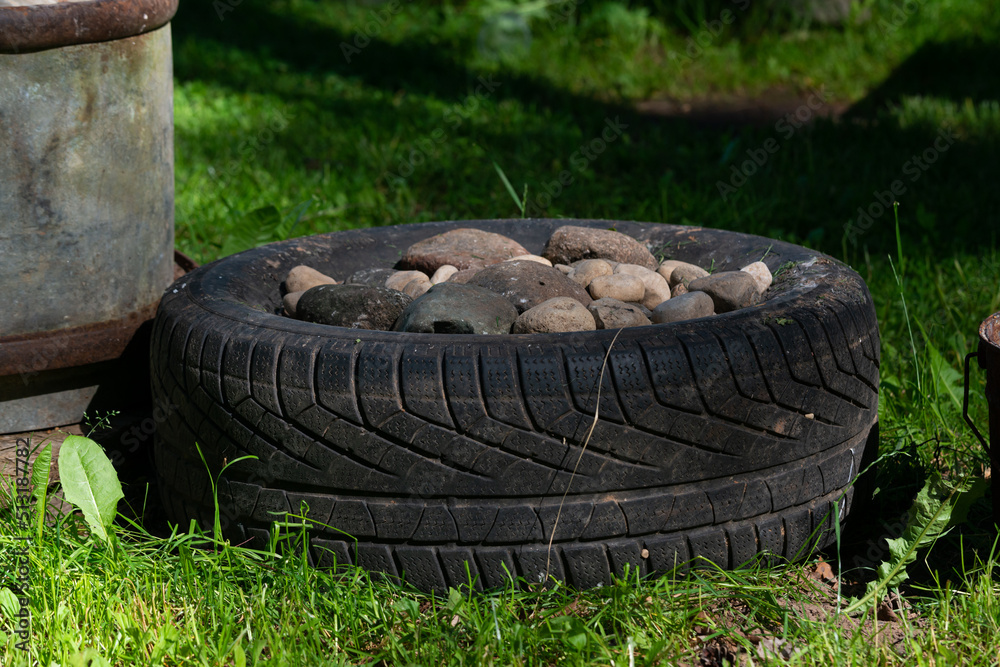 The car tire in the forest in the green grass is loaded full of stone ...