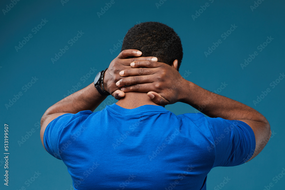 Back view of muscular black man with hands on neck wearing blue against ...