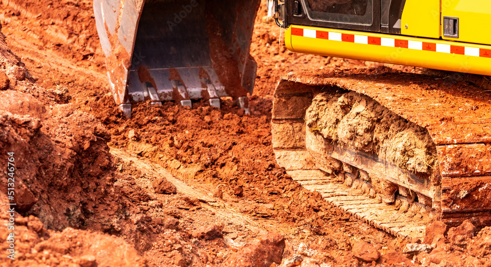 Backhoe working by digging soil at construction site. Bucket of backhoe ...