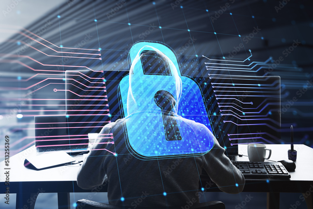 Back view of hacker at desktop using computers with glowing padlock ...