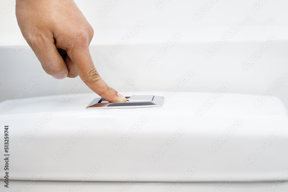Close up of finger pushing button hand press and flush toilet after ...