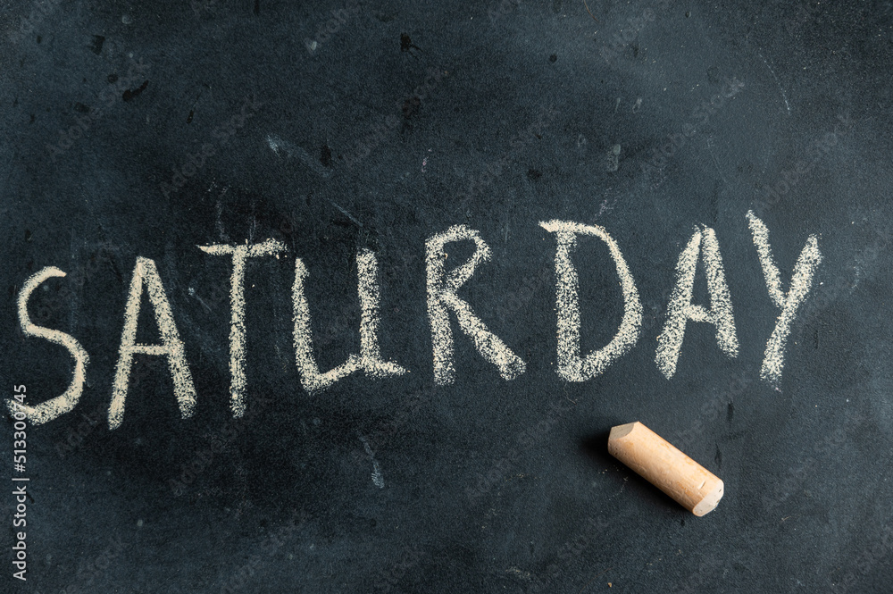 Saturday. Name of the day of the week written in yellow chalk on black ...