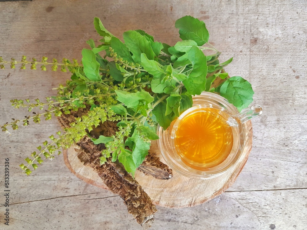 Tulsi tea is served in a cup with fresh leaves on the side of the ...