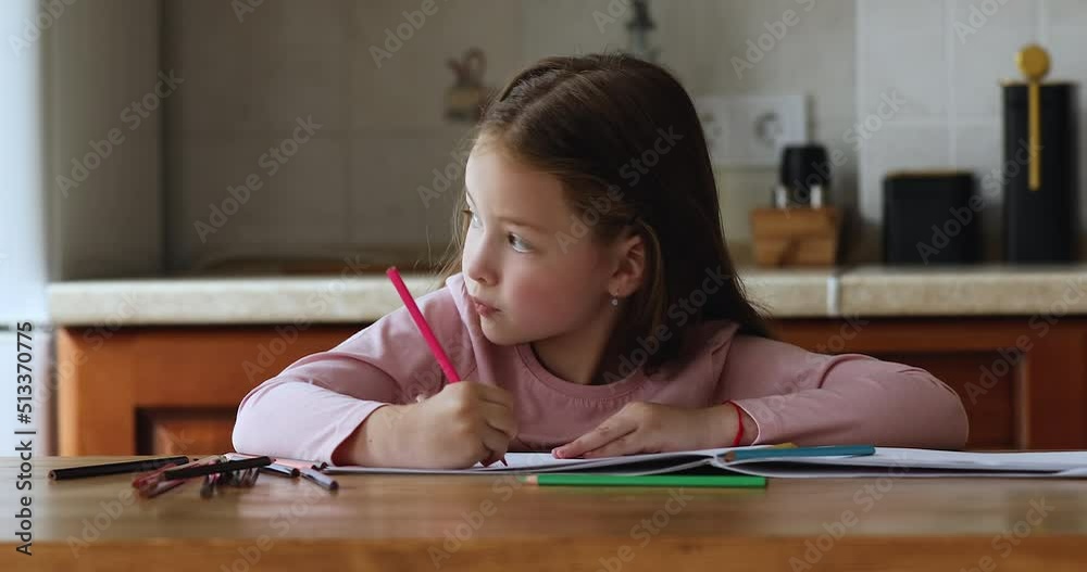 Focused sweet primary school kid doing homework, learning to write ...