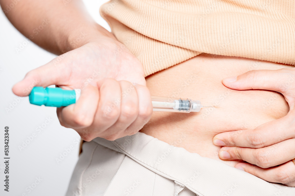 Woman making hormonal therapy injection into her belly. Close up ...