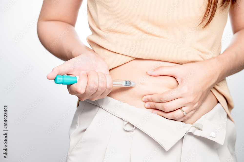 Woman making hormonal therapy injection into her belly. Close up ...