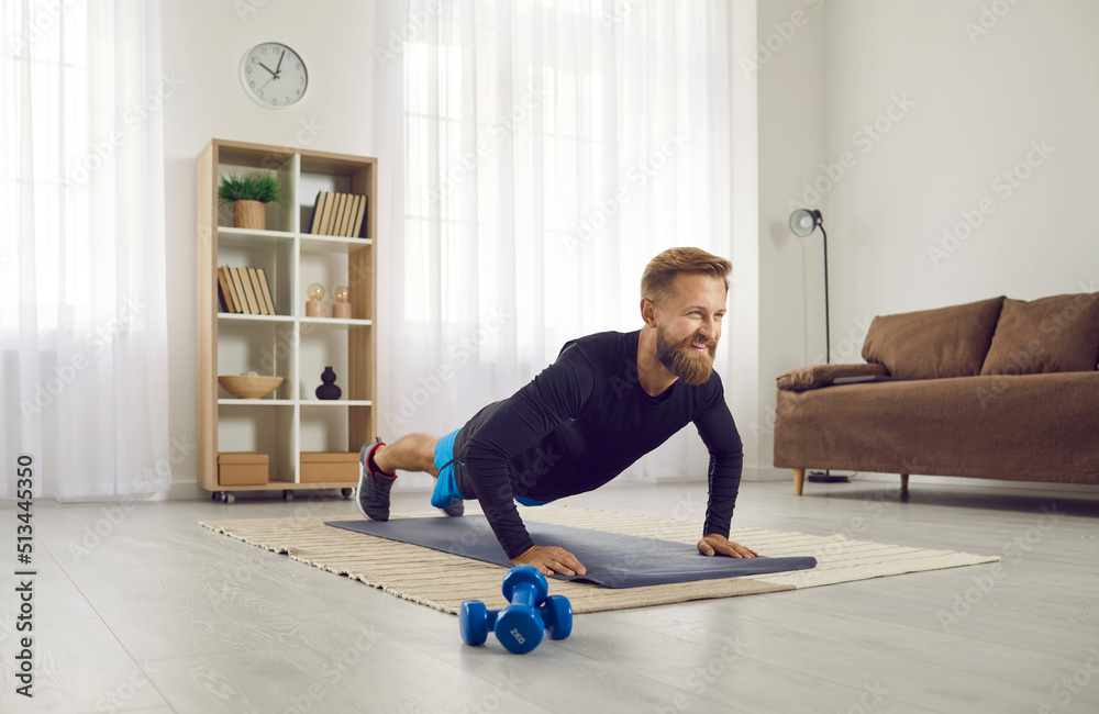 Smiling active young man do pushups on mat on lockdown at home. Happy ...