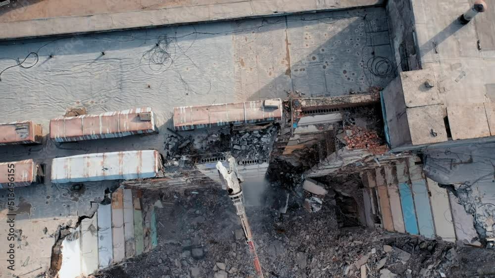 Tall building destroyed. Demolition machine tearing down roof of a ...