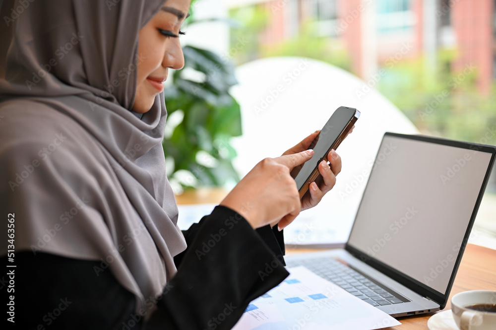 Charming young muslim woman with hijab at her office desk using ...
