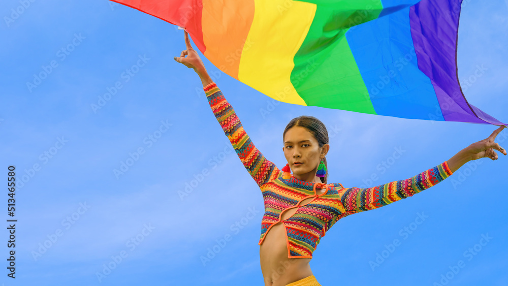 transgender person posing with pride flag in celebration of pride month ...