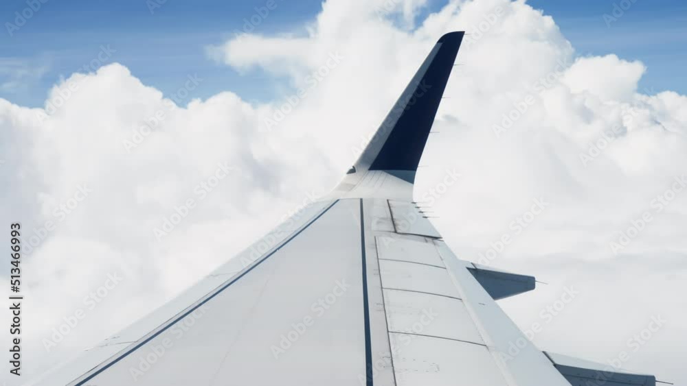 Wing of an airplane leaning down and changing direction of flight with ...