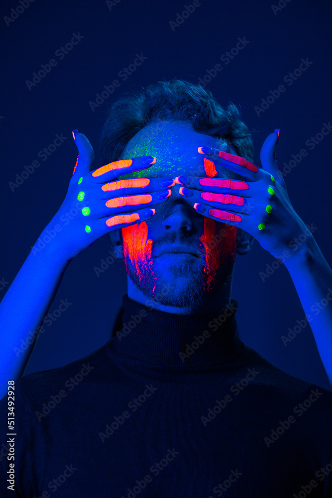 Man and woman model with fluorescent paint on face posing under ...