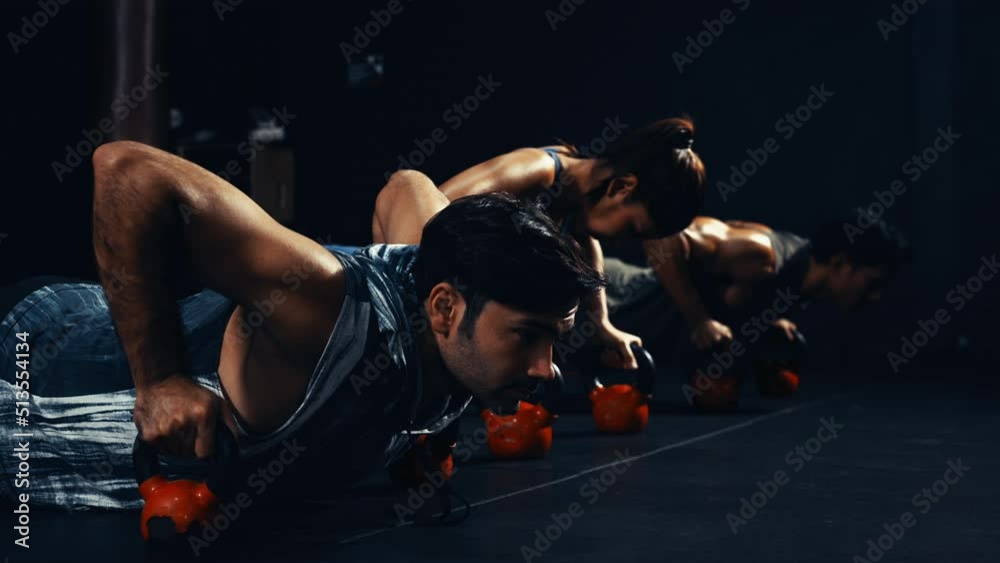 Sporty group of people doing push-ups on weights workout exercise in ...