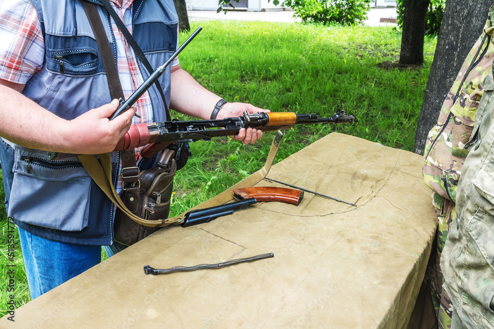 Poster A man is learning how to assemble a machine gun on a military ...