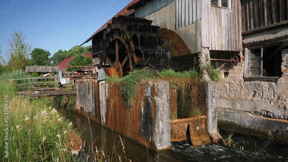 Wooden wheel of old mill turning water. Mill wheel rotates under stream ...