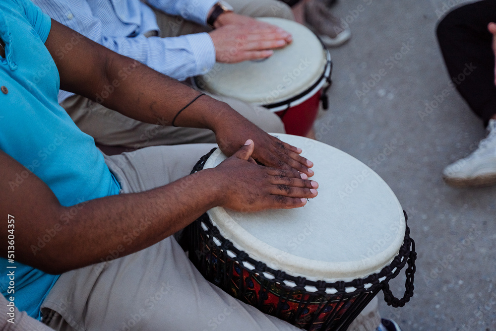 Drumming close-up, a black guy beats the rhythm on a djmba, a street ...