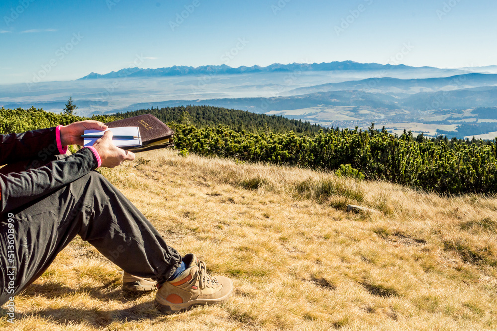 Outdoor Bible study during mountain hike. Female hands holding a Bible ...