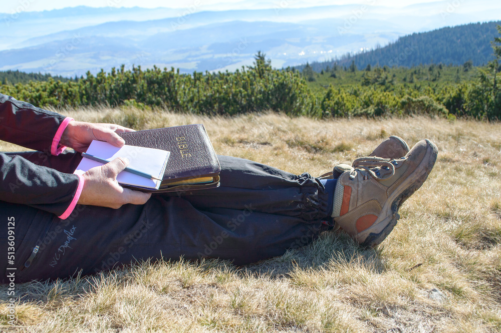 Outdoor Bible study during mountain hike. Female hands holding a Bible ...